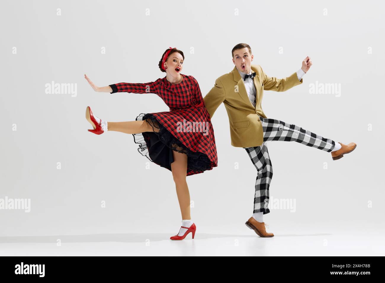 Young man in checkered trousers and mustard jacket dancing with woman ...