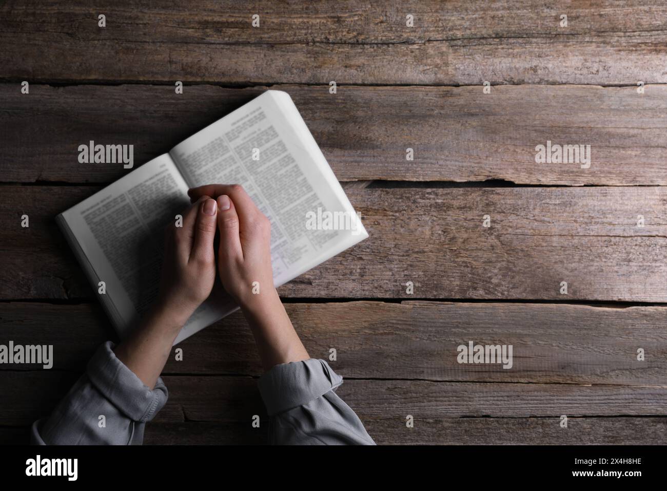 Religion. Christian woman praying over Bible at wooden table, top view ...