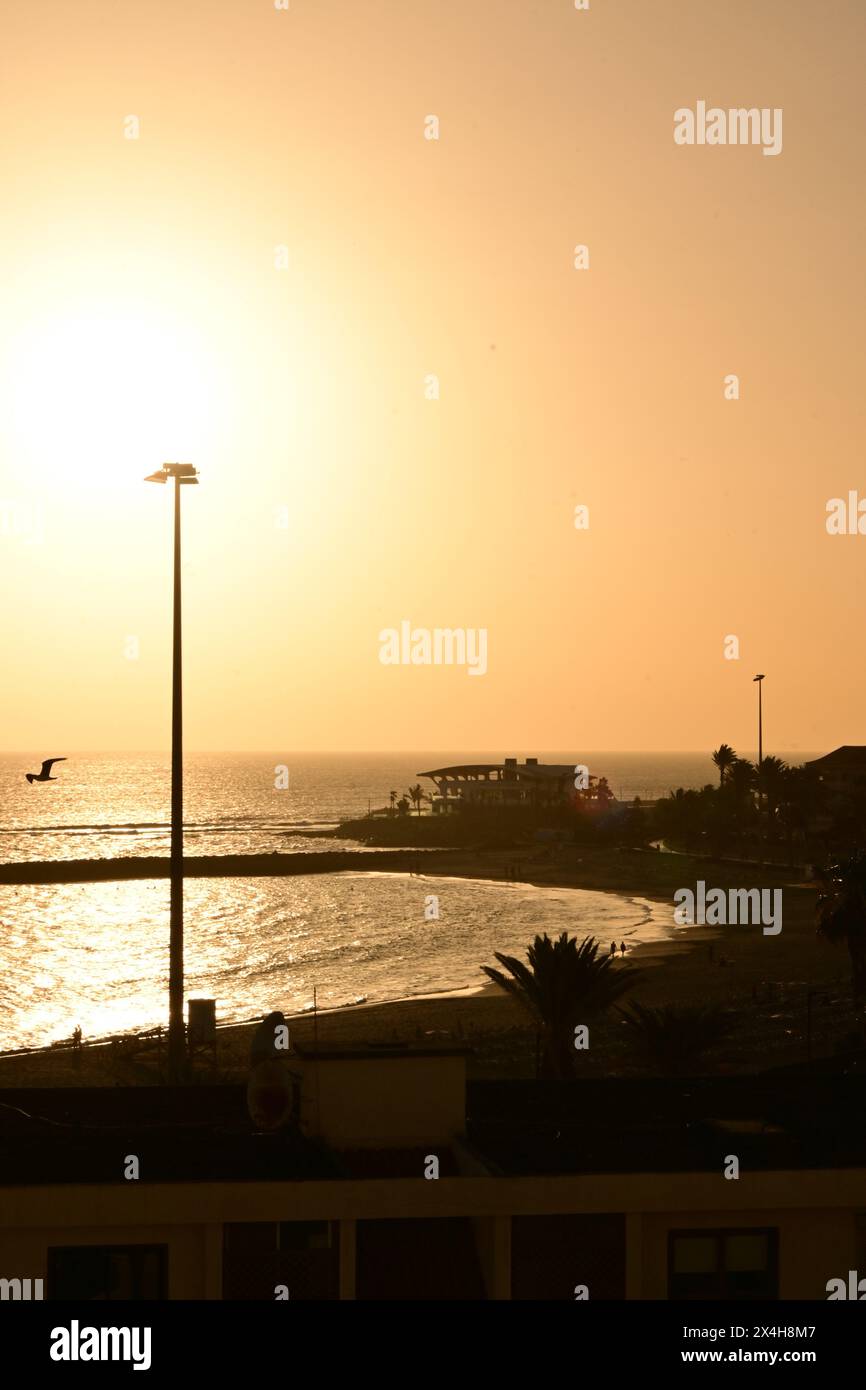 sunset at the beach with the sun setting over the horizon, casting a ...