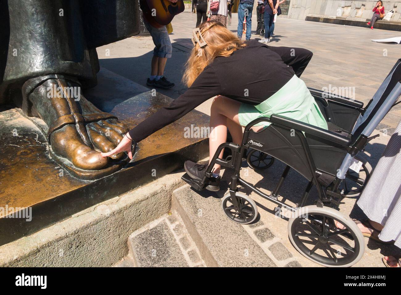 Model released child in wheelchair rubs left foot toe on Statue of St ...