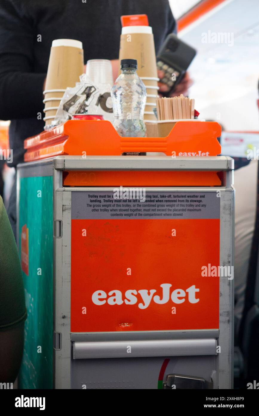 Cabin crew / air steward serves drinks and snacks to passengers from a ...