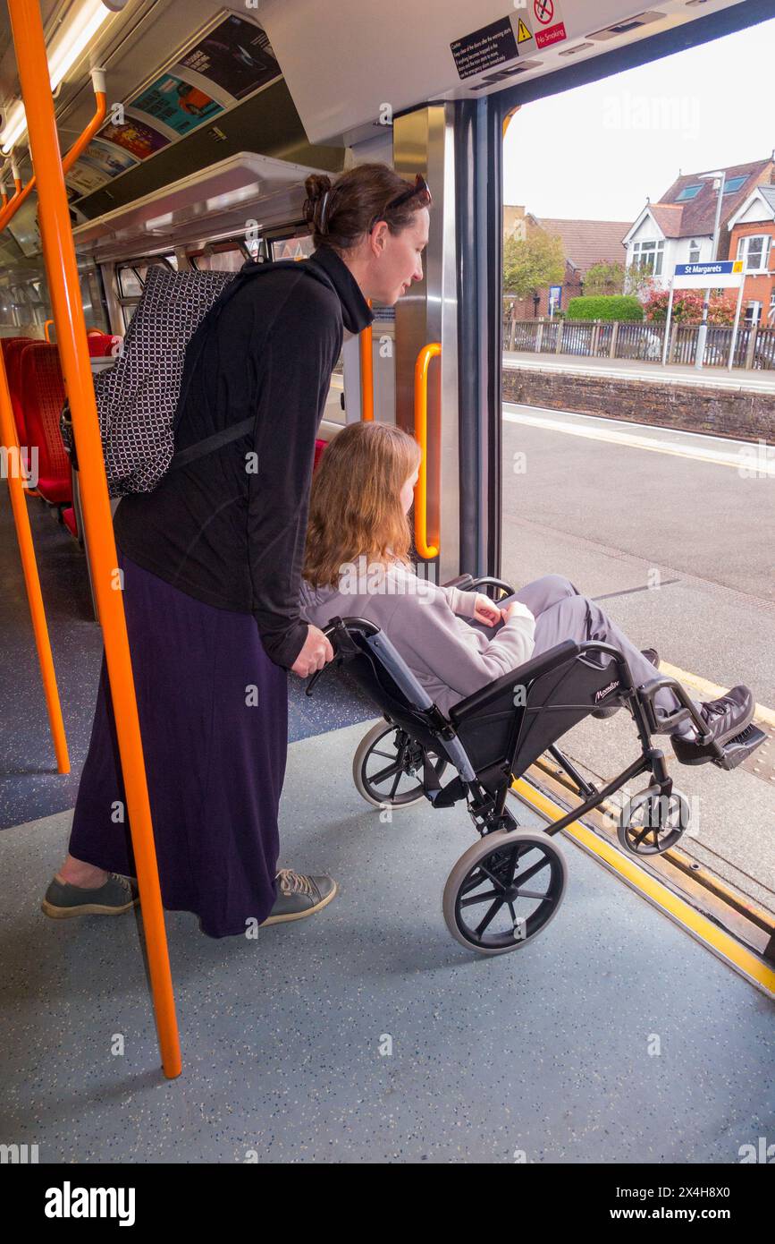 Mother and disabled daughter / girl using a wheelchair at access door ...