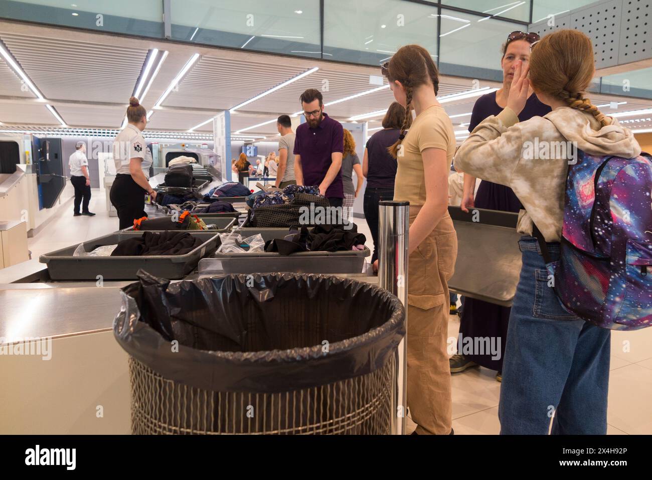 Mum and children / kids at the start of airport security search and X Ray scanning check at ...