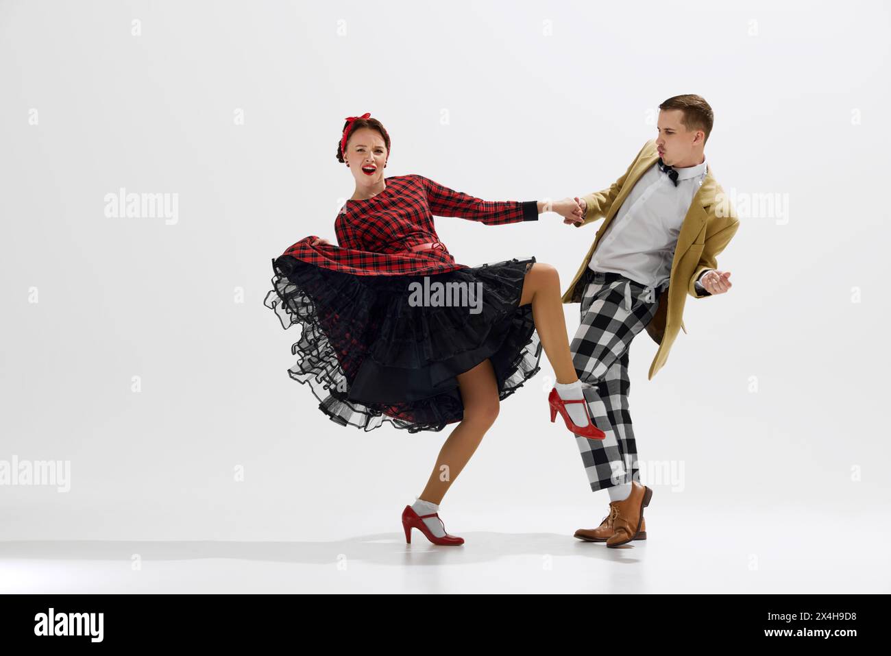 Stylish and playful couple in 1950s style clothes performing dynamic ...