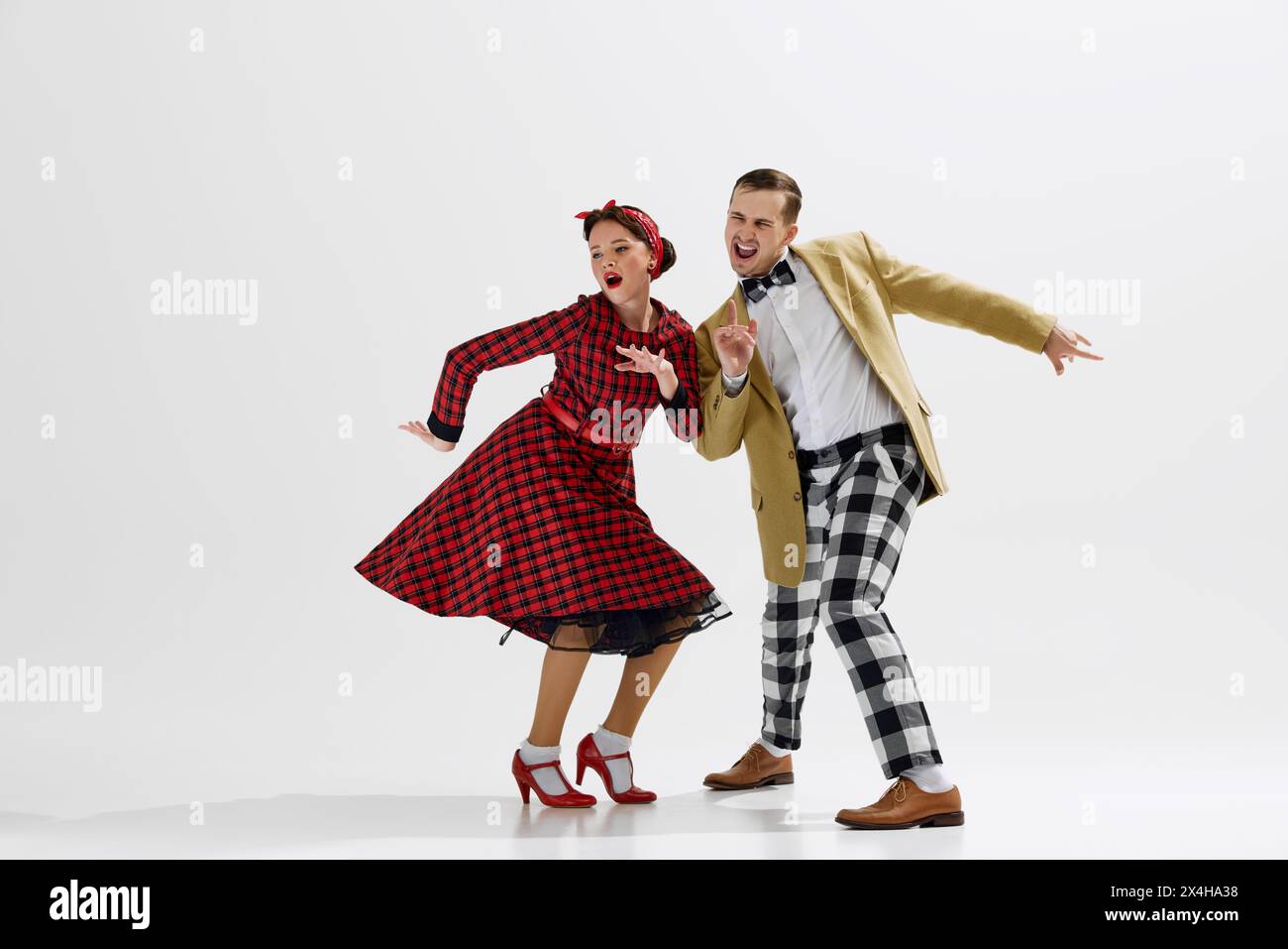 Man in checkered trousers and mustard jacket dancing with woman in red ...