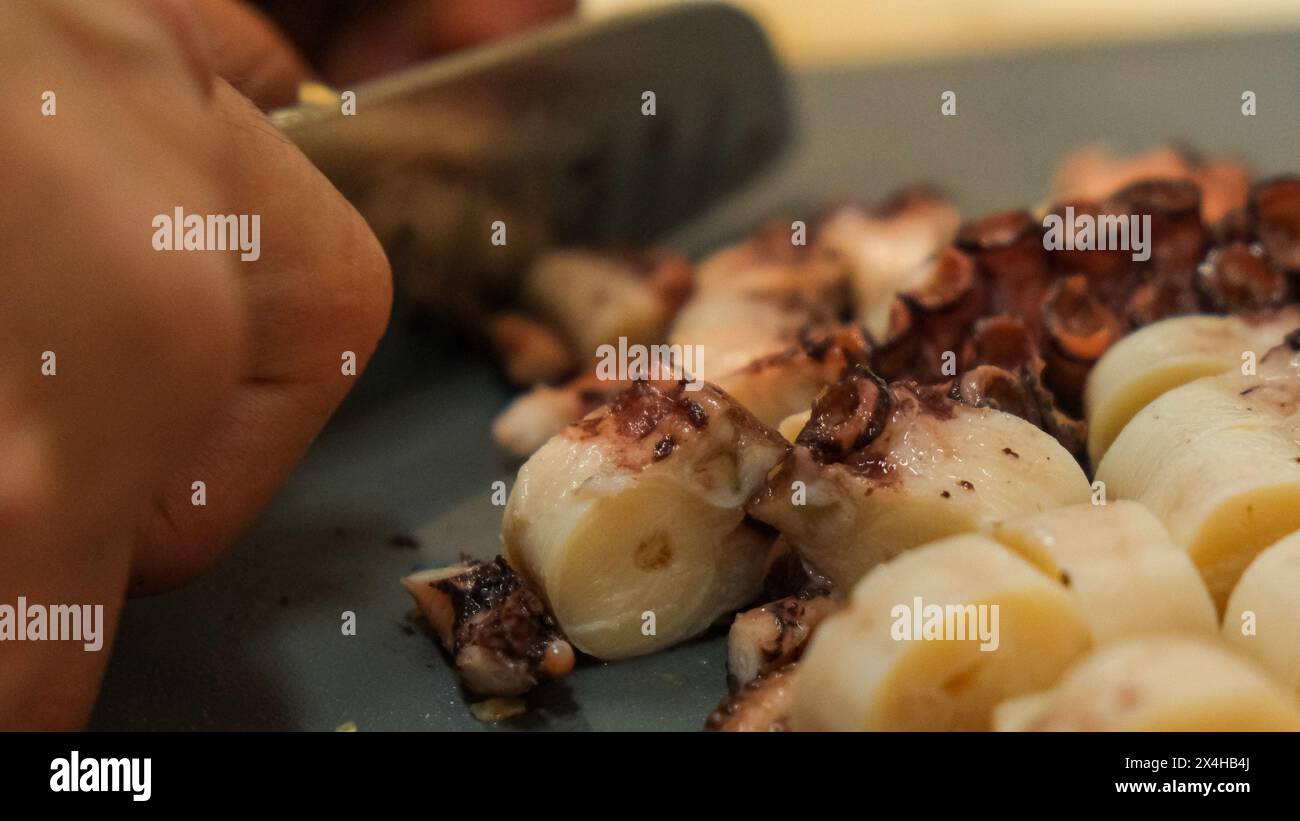 Close up uncooked octopus cutting with knife by chief. Man´s hand ...