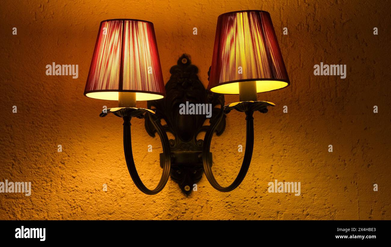 Close up vintage wall-mounted double lamp with ornate ironwork. The two ...