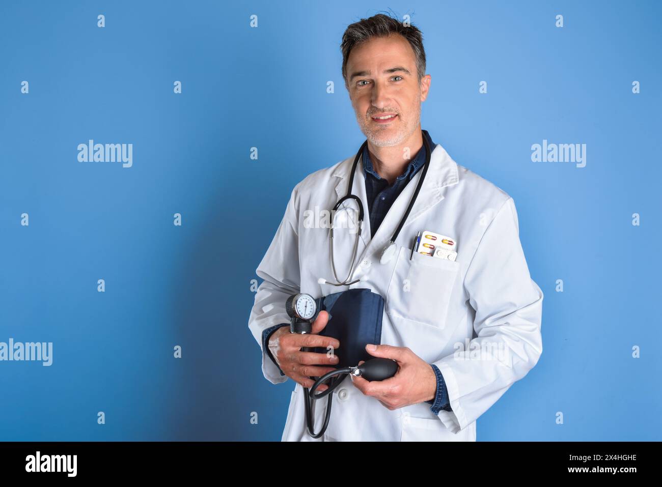 Portrait of doctor in white coat showing manual blood pressure monitor ...