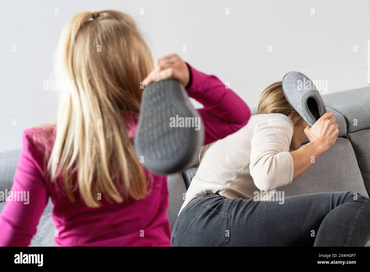Young girl in pink retaliates by holding a slipper up against her ...