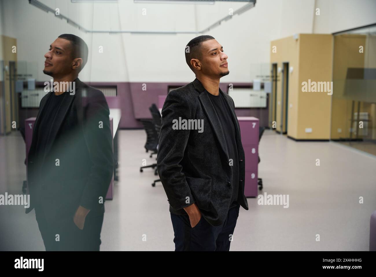Calm young manager standing while putting hands in pockets Stock Photo ...