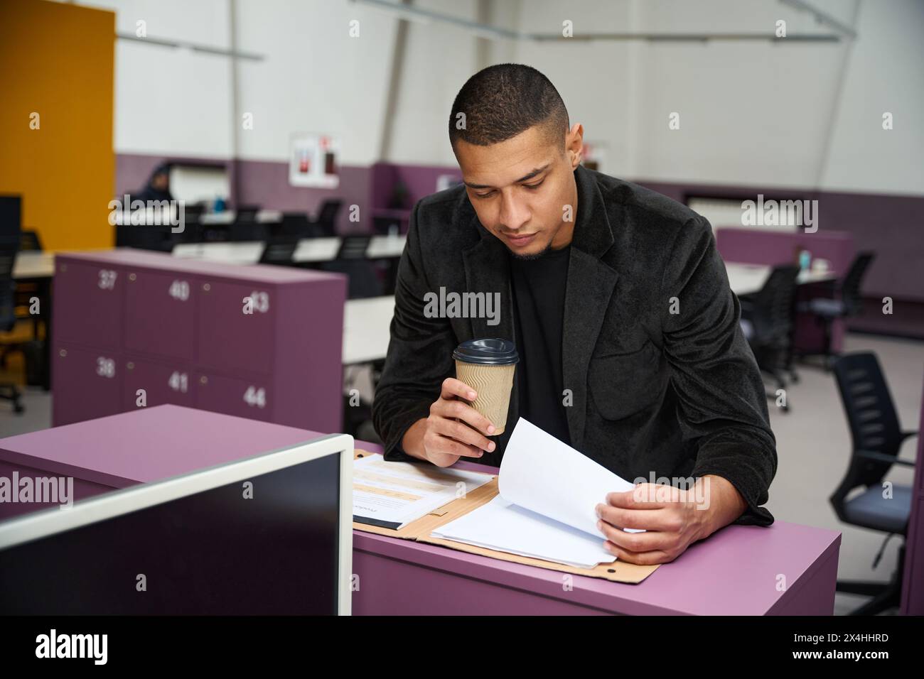 Concentrated young man looking through documents while standing in ...