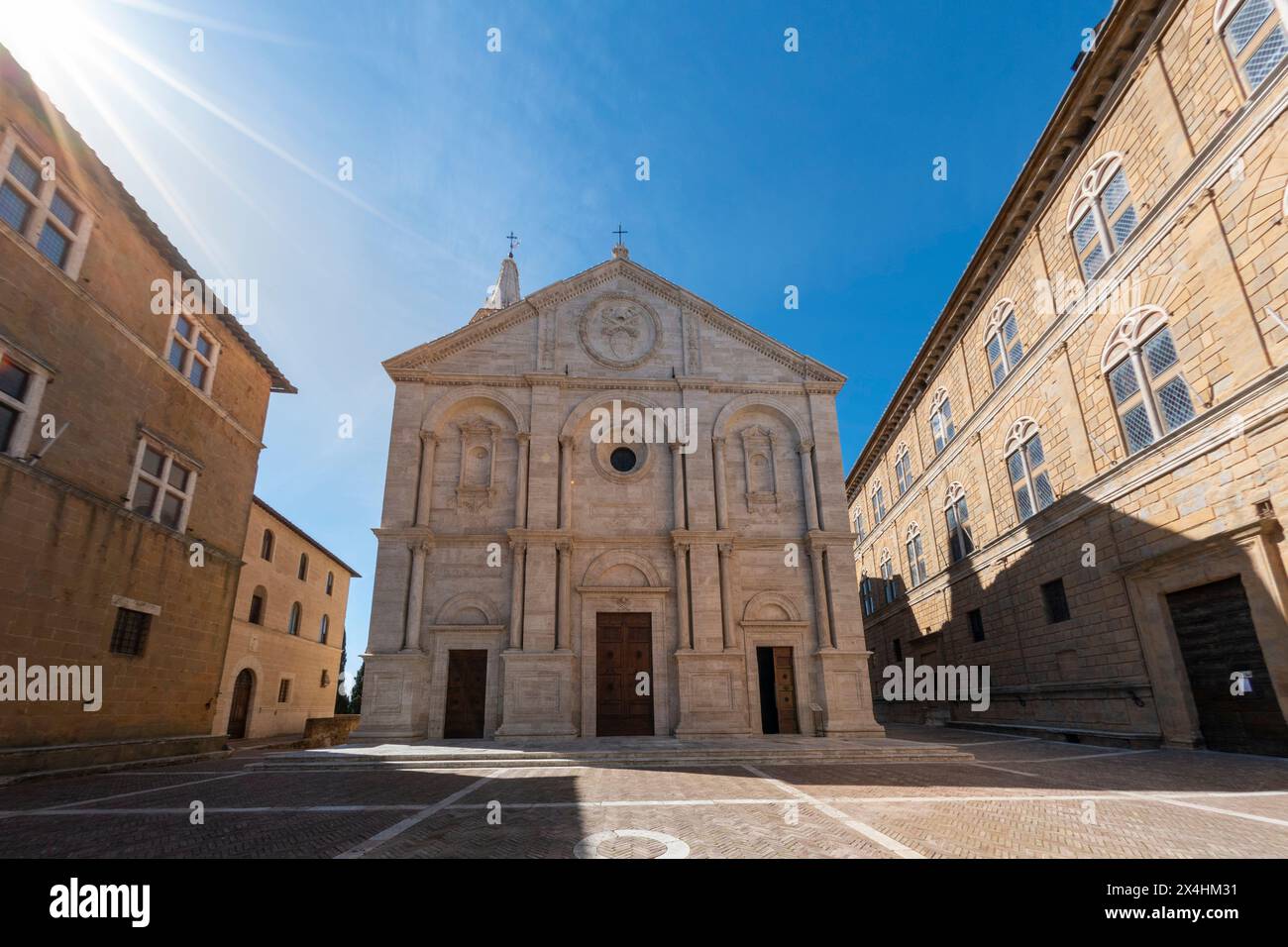 Facade of a historic cathedral with a clear blue sky and sun rays ...