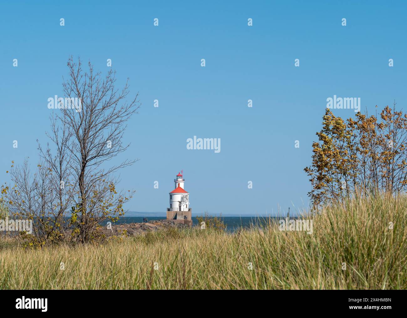 Lighthouse with red roof on Lake Superior at the end of a pier, autumn ...