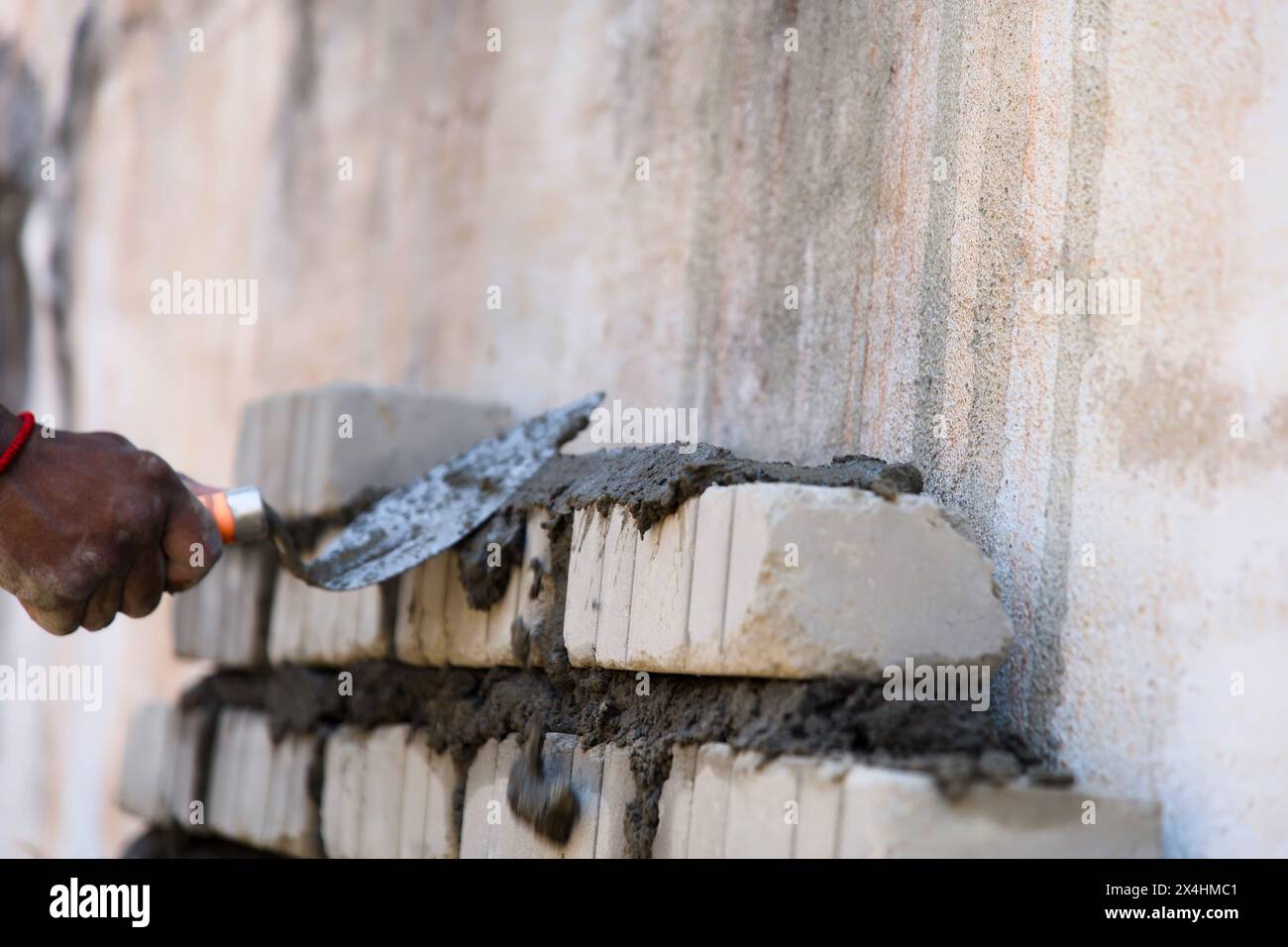 A concentrated construction worker meticulously smooths a layer of ...