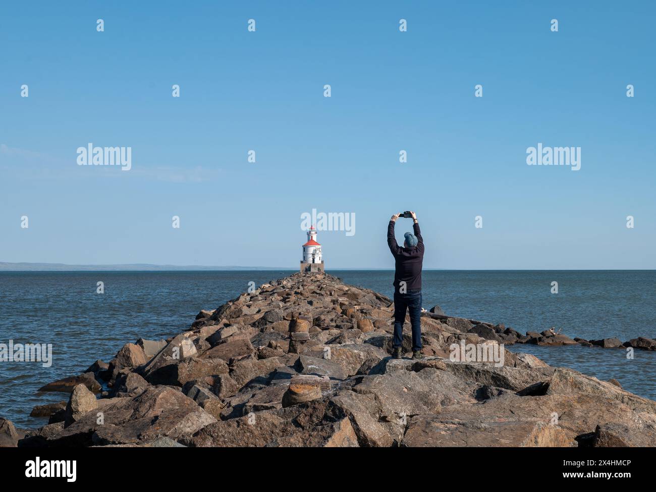 Unidentifiable photographer takes picture of a lighthouse with red roof ...