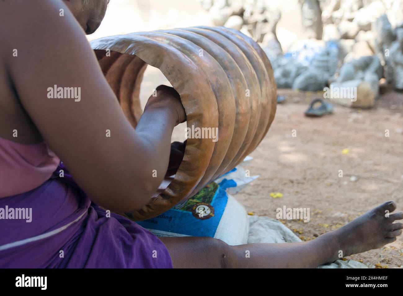 A dedicated Indian sculptor meticulously works on a metal form ...