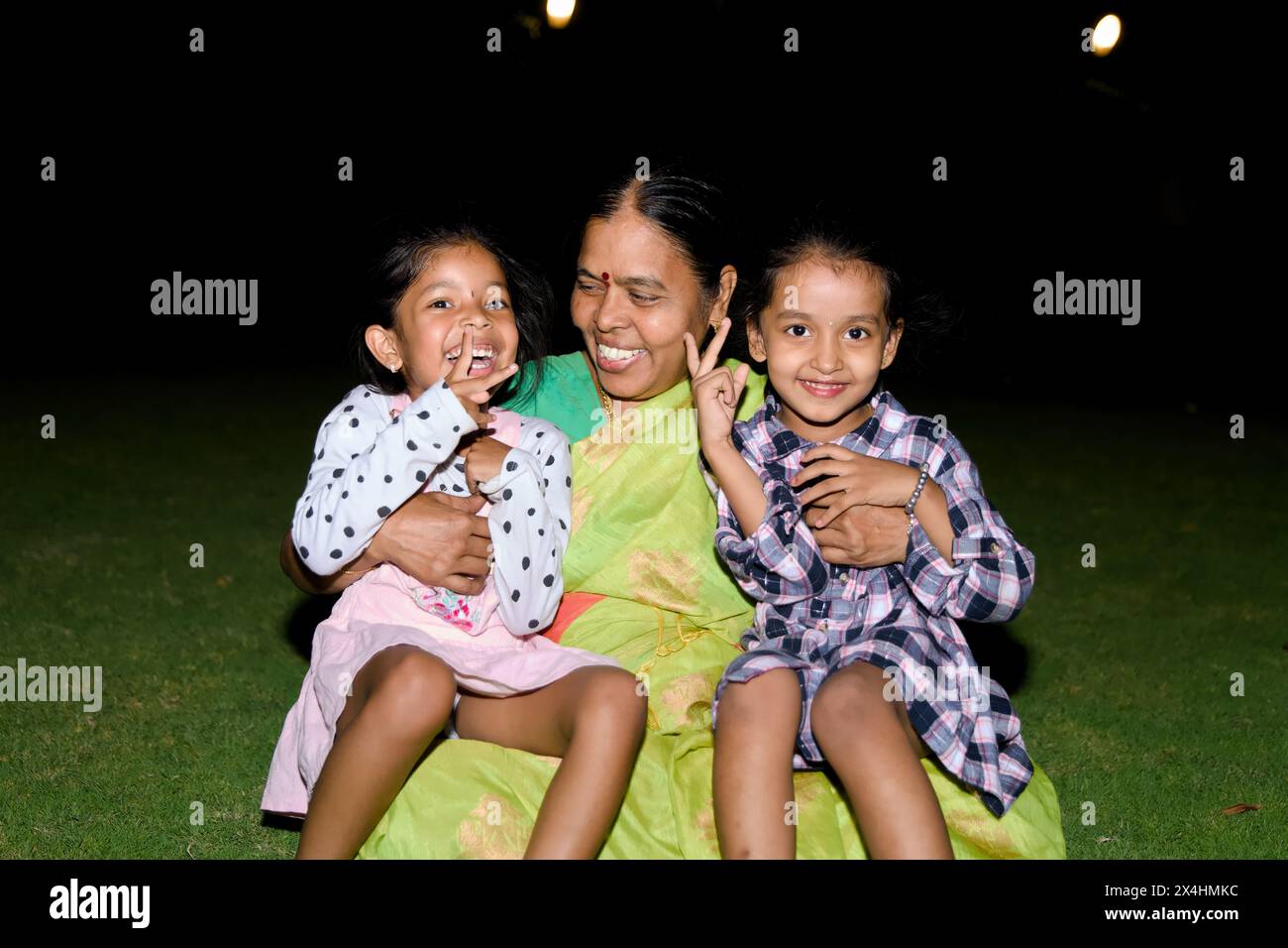 A content Indian grandmother smiles as she embraces her two ...