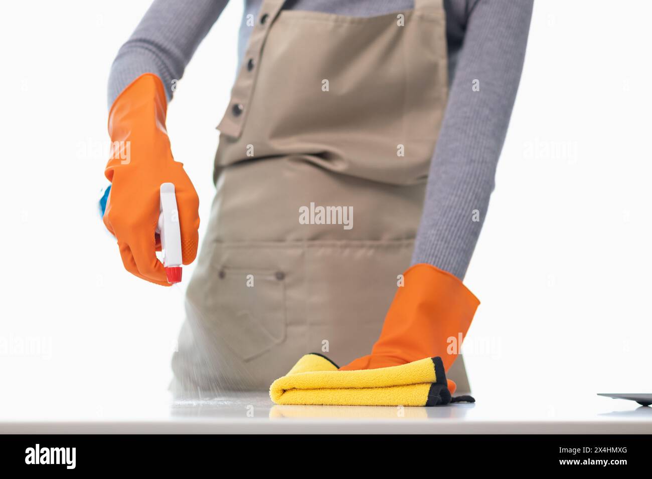 young woman puts on an apron and rubber gloves before holding spray ...