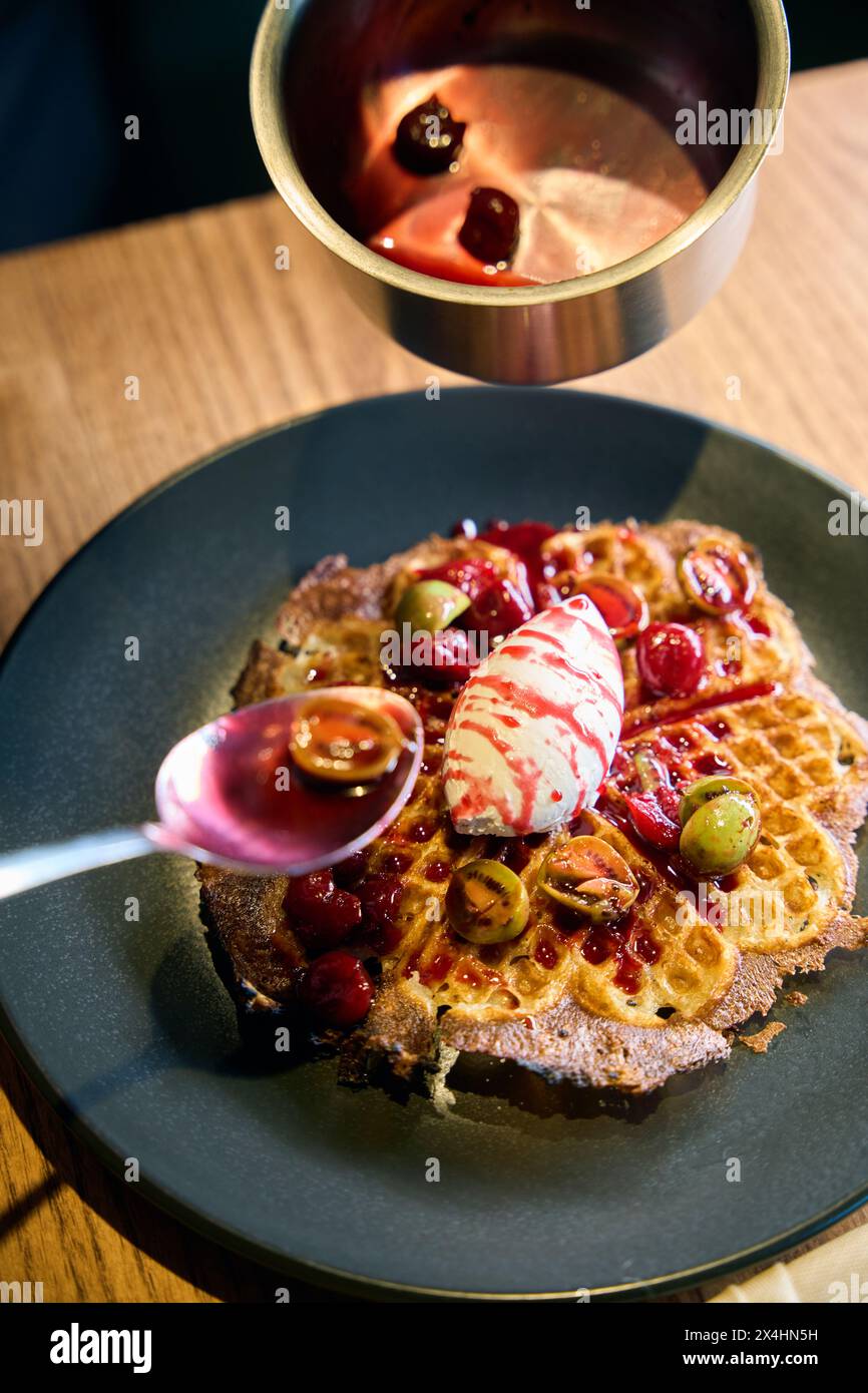 Top view of cropped male chef adding kiwis and cherries in jam to ...