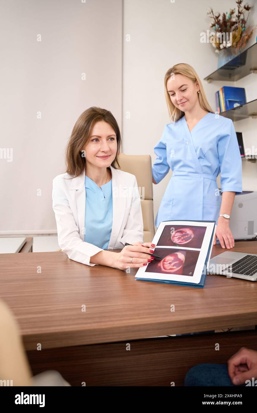 Gynecologist showing to couple results of ultrasound scanning of woman ...
