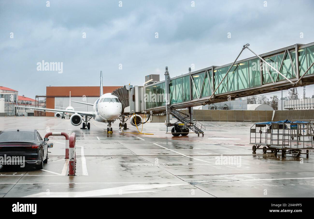 Commercial airplane docked at the gate on rainy day with boarding ...