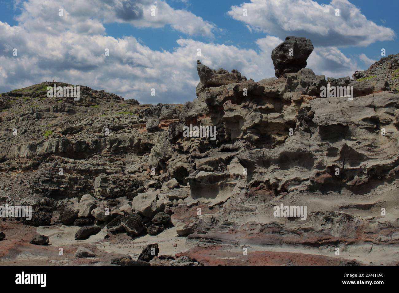 A steep hill composed of rough and sharp volcanic rock, with tourists ...