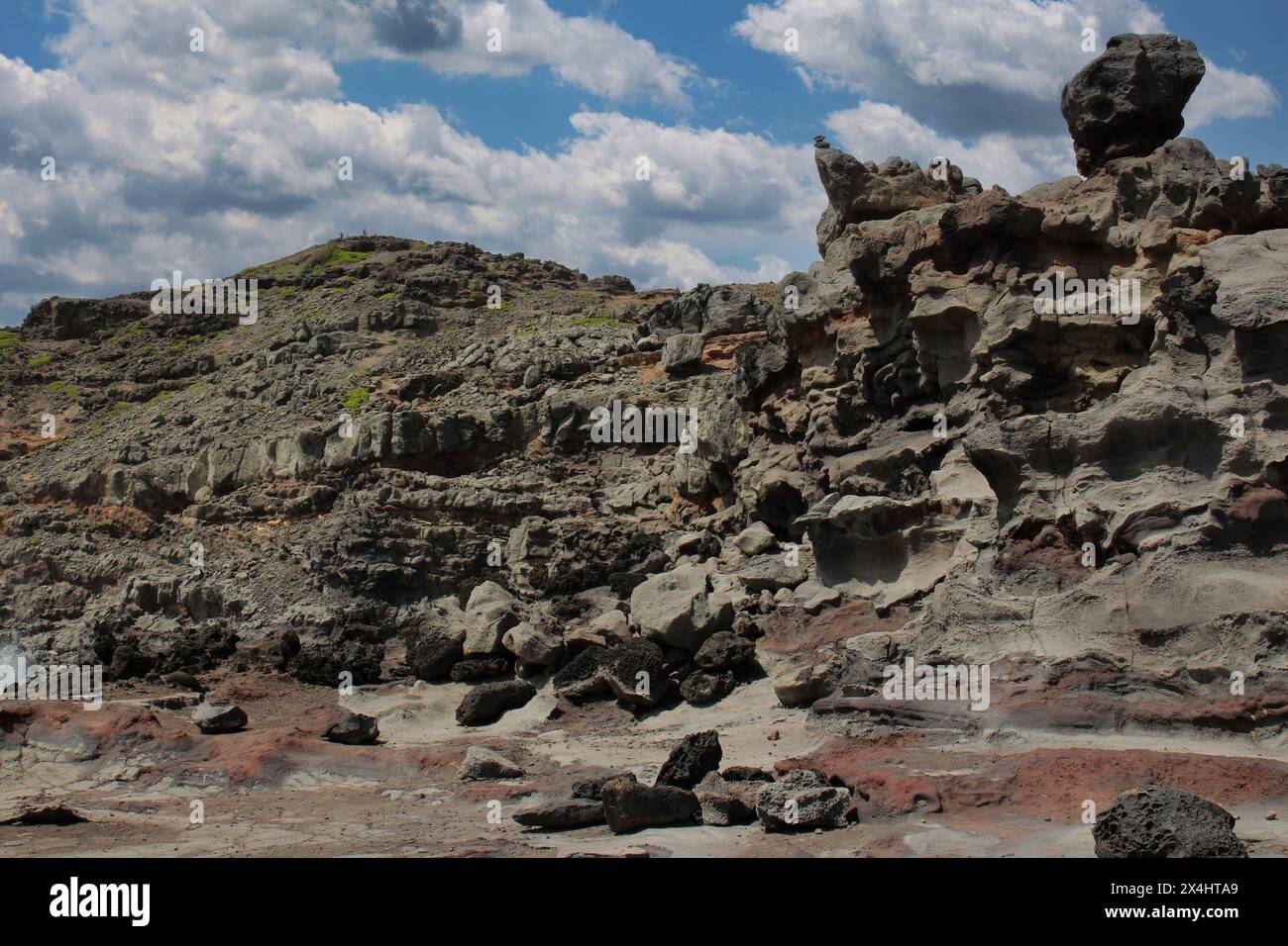A steep hill composed of rough and sharp volcanic rock, with tourists ...