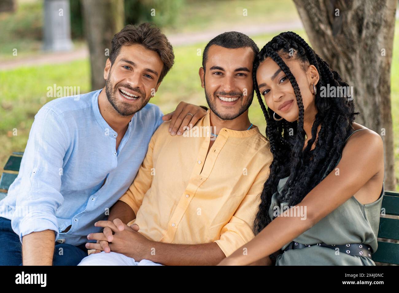 Three young, multicultural friends - smiling and embracing in an urban ...