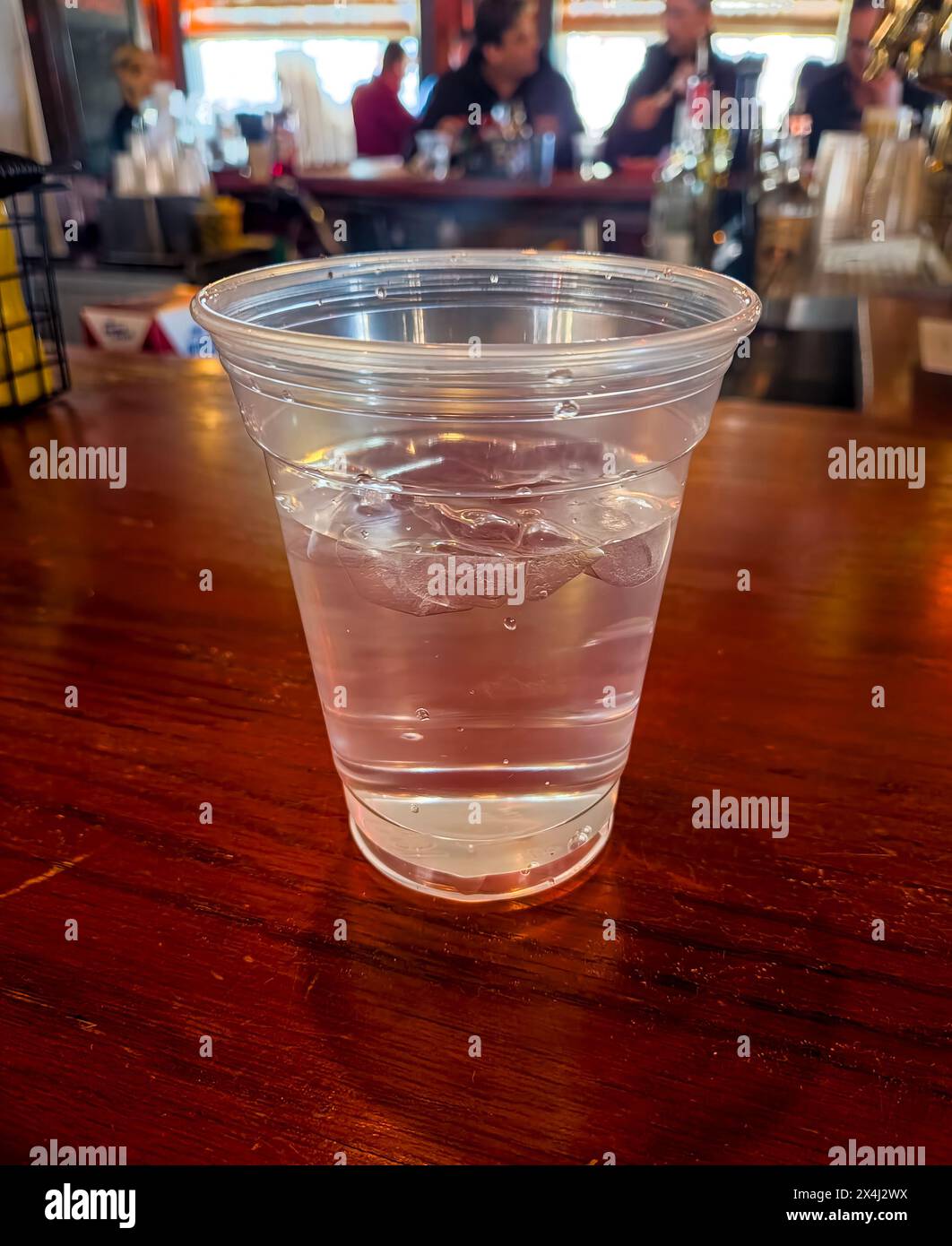 Cup of water with ice at a crowded bar Stock Photo - Alamy