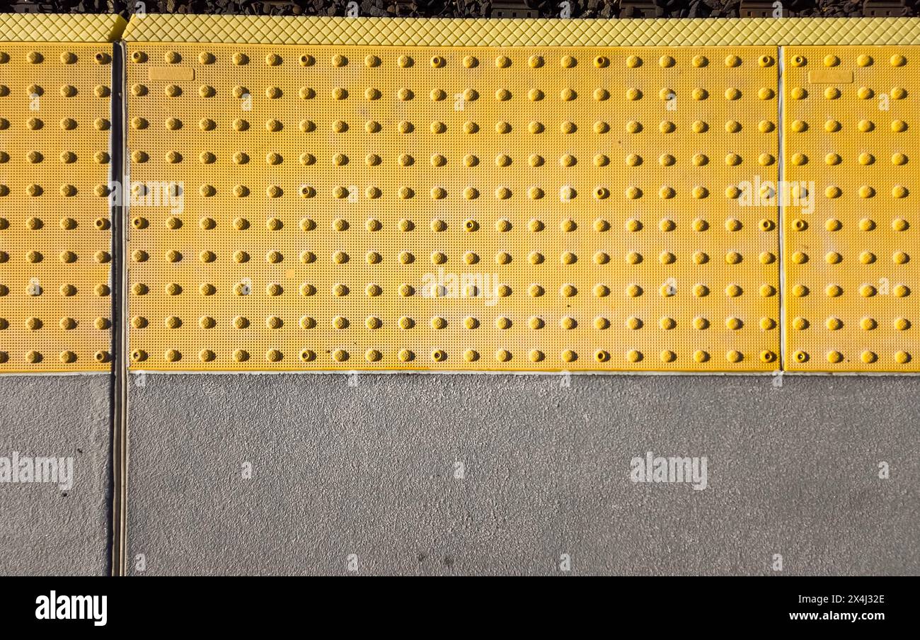 Yellow warning tile bumps in front of train tracks Stock Photo - Alamy
