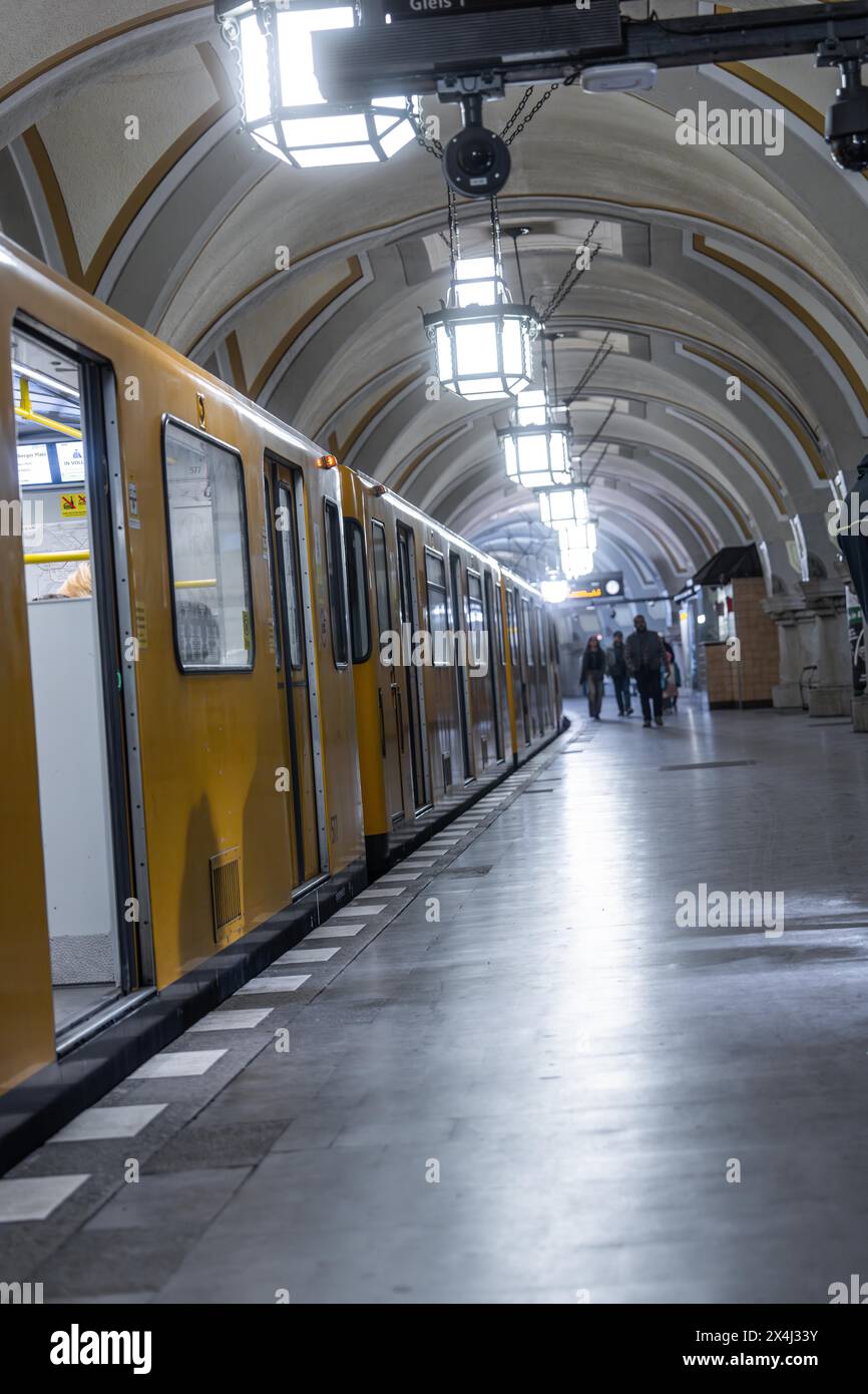 A yellow underground train stops at an arched platform underground ...