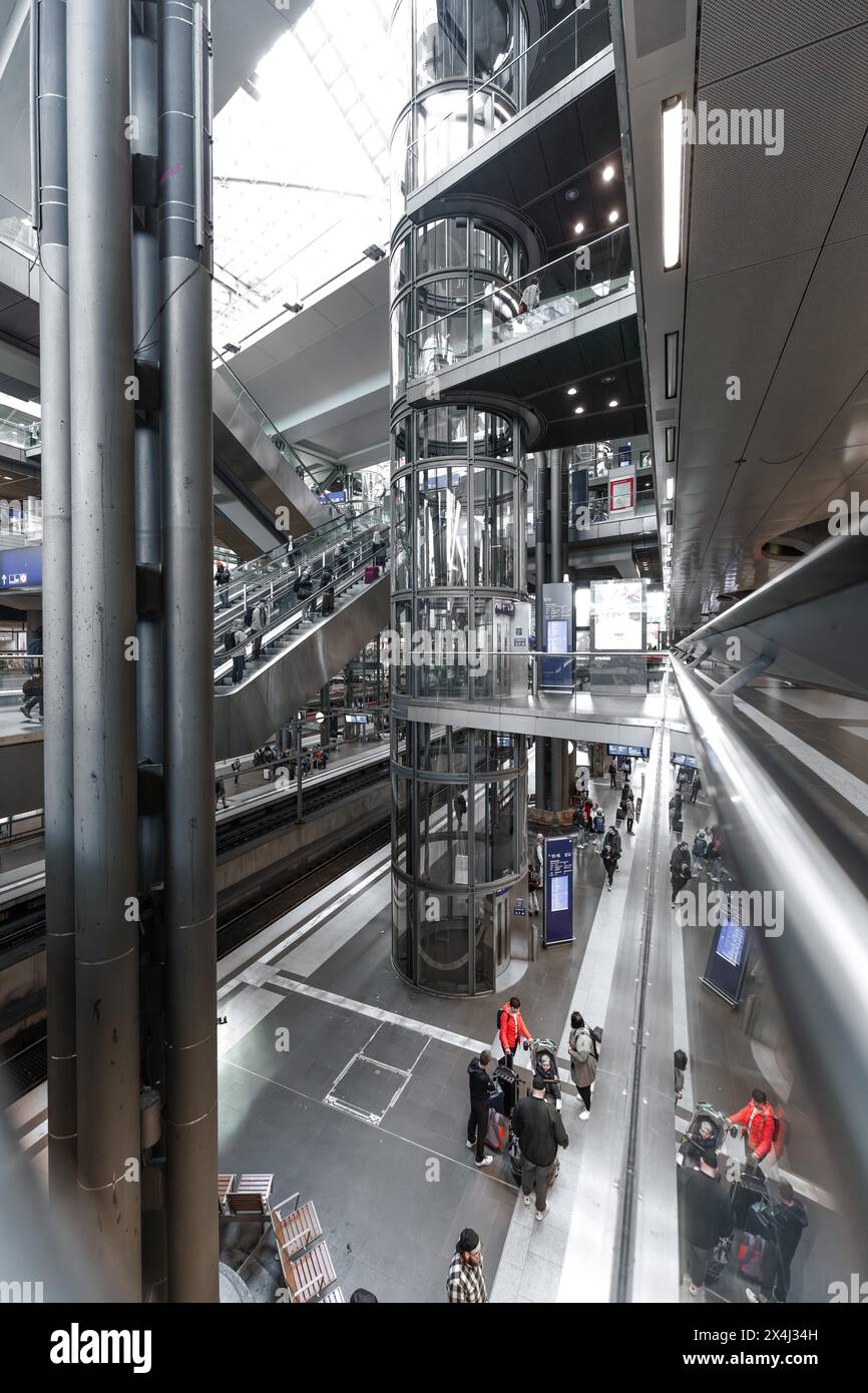 Multi-storey railway station with glass facade and people on different ...