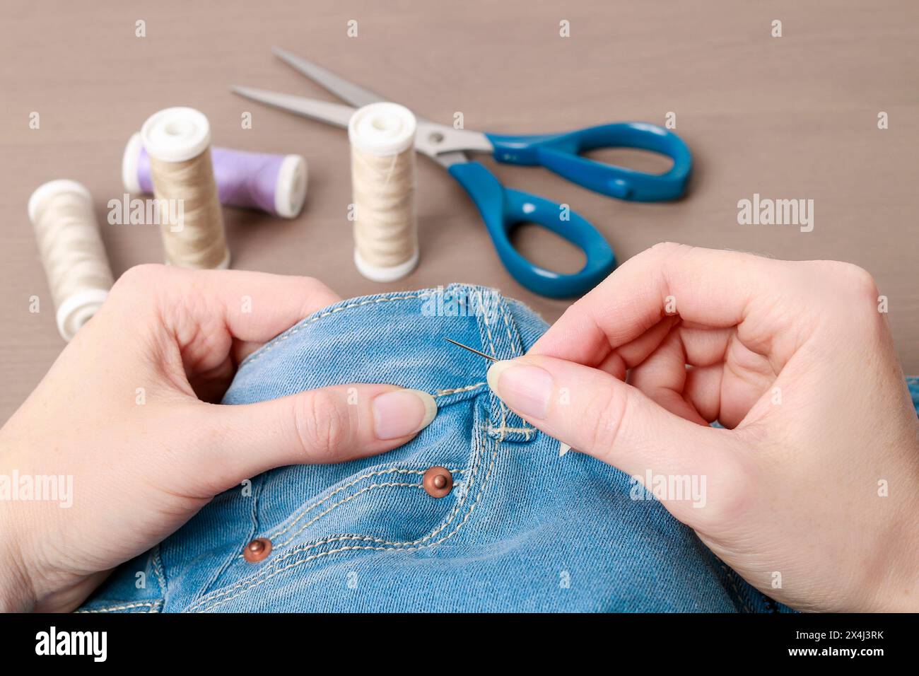 Woman repairing a pair of blue jeans. Hobby time Stock Photo - Alamy
