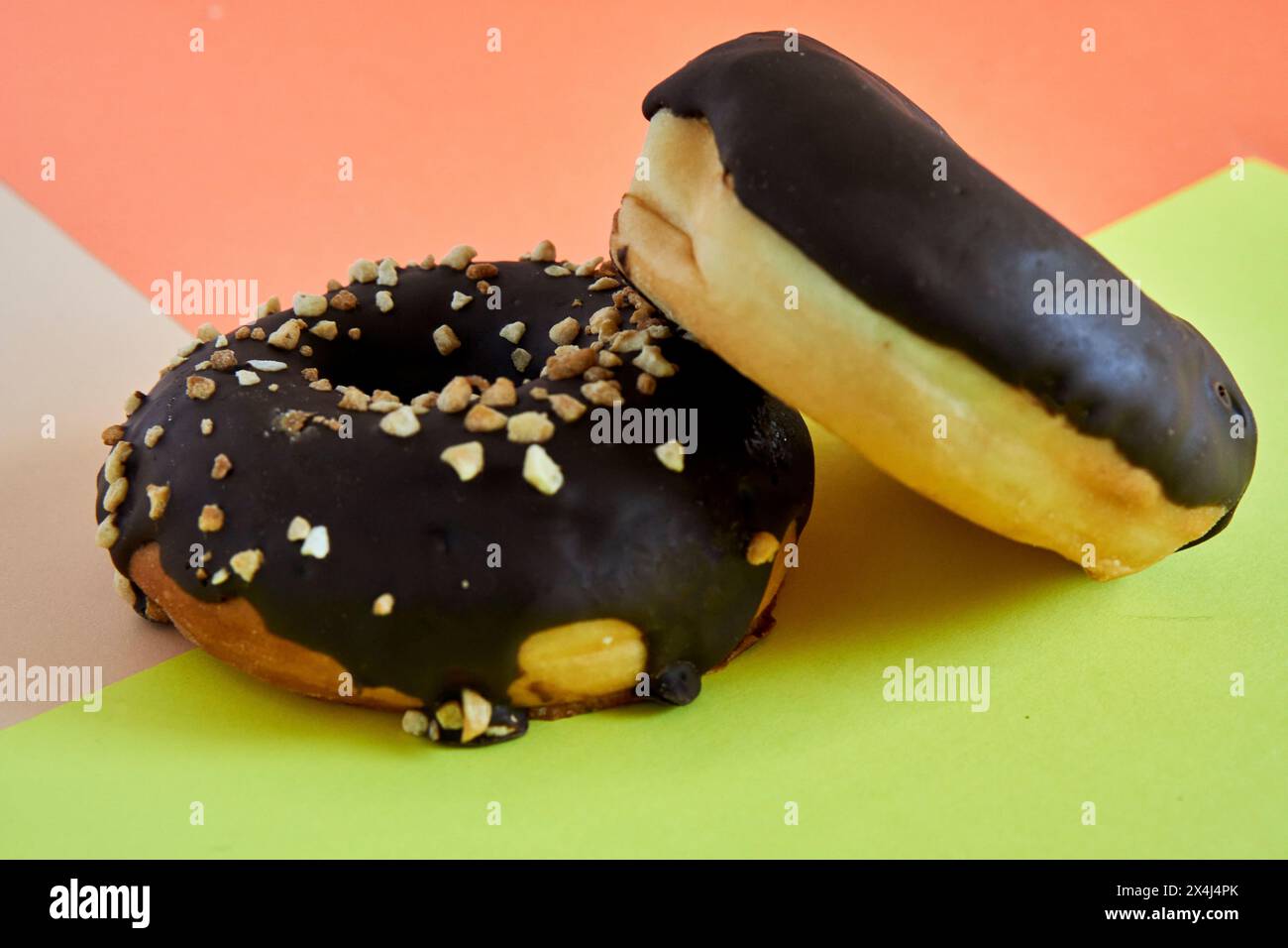 two Chocolate covered donuts with crush nuts on top on colored ...