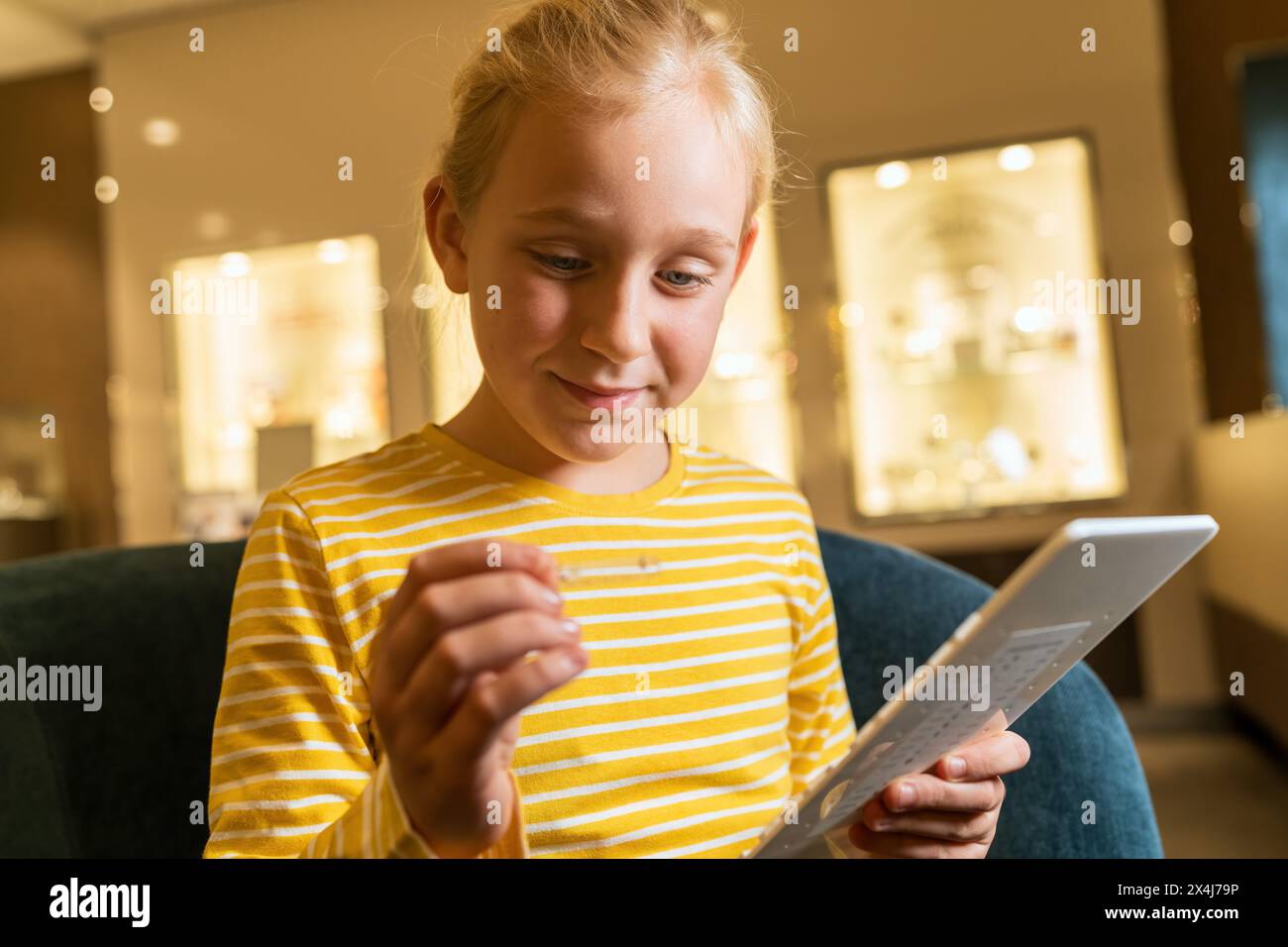 Young girl smiling and focused on eaaring display to choose her ...