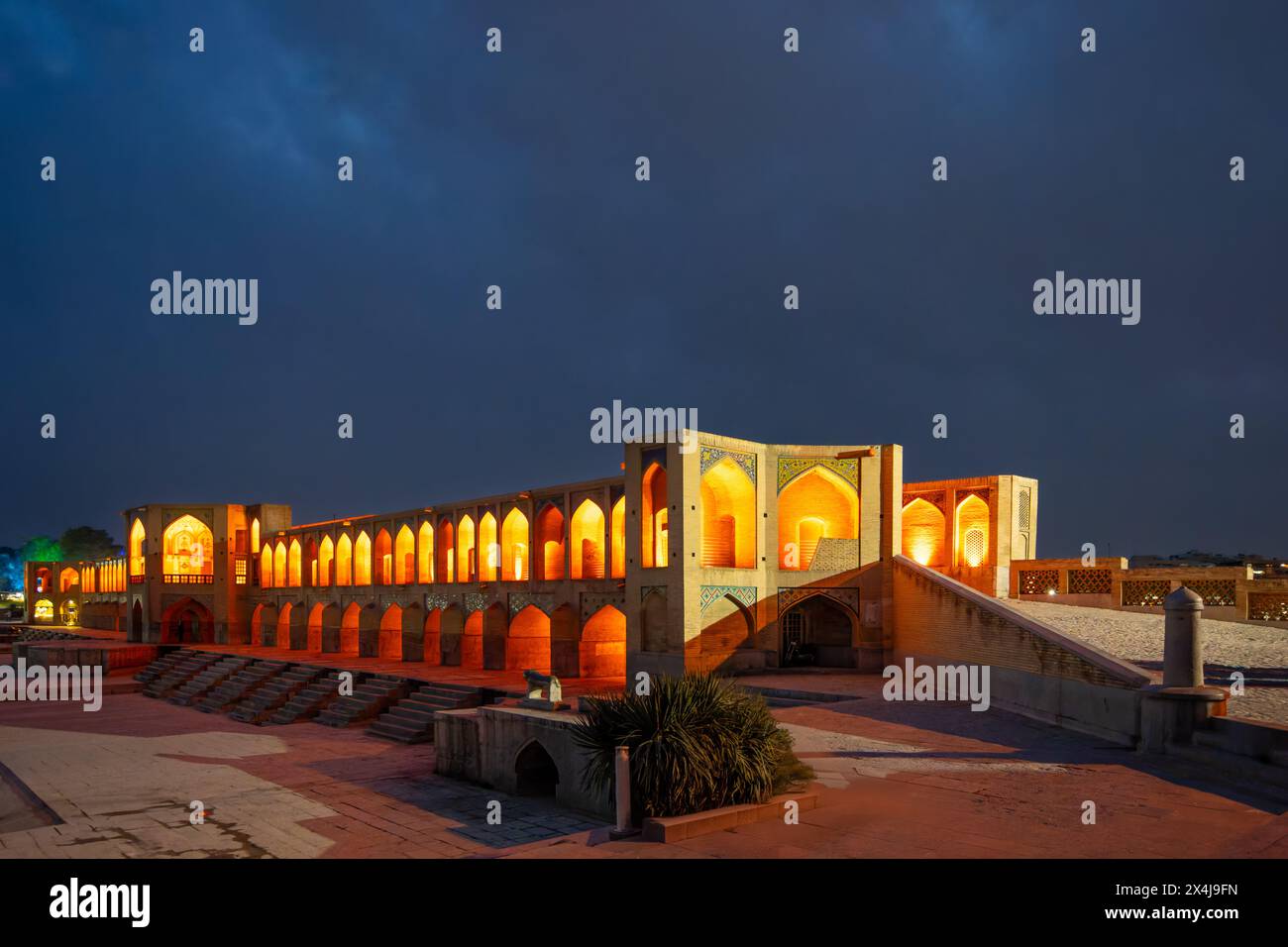 The historic Khaju Bridge glows with vibrant orange lights under the ...