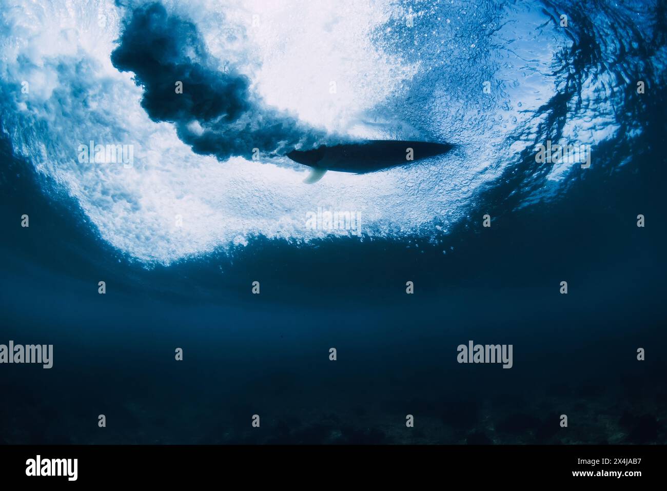 Surfer on surfboard in ocean underwater view. Crashing wave and ...