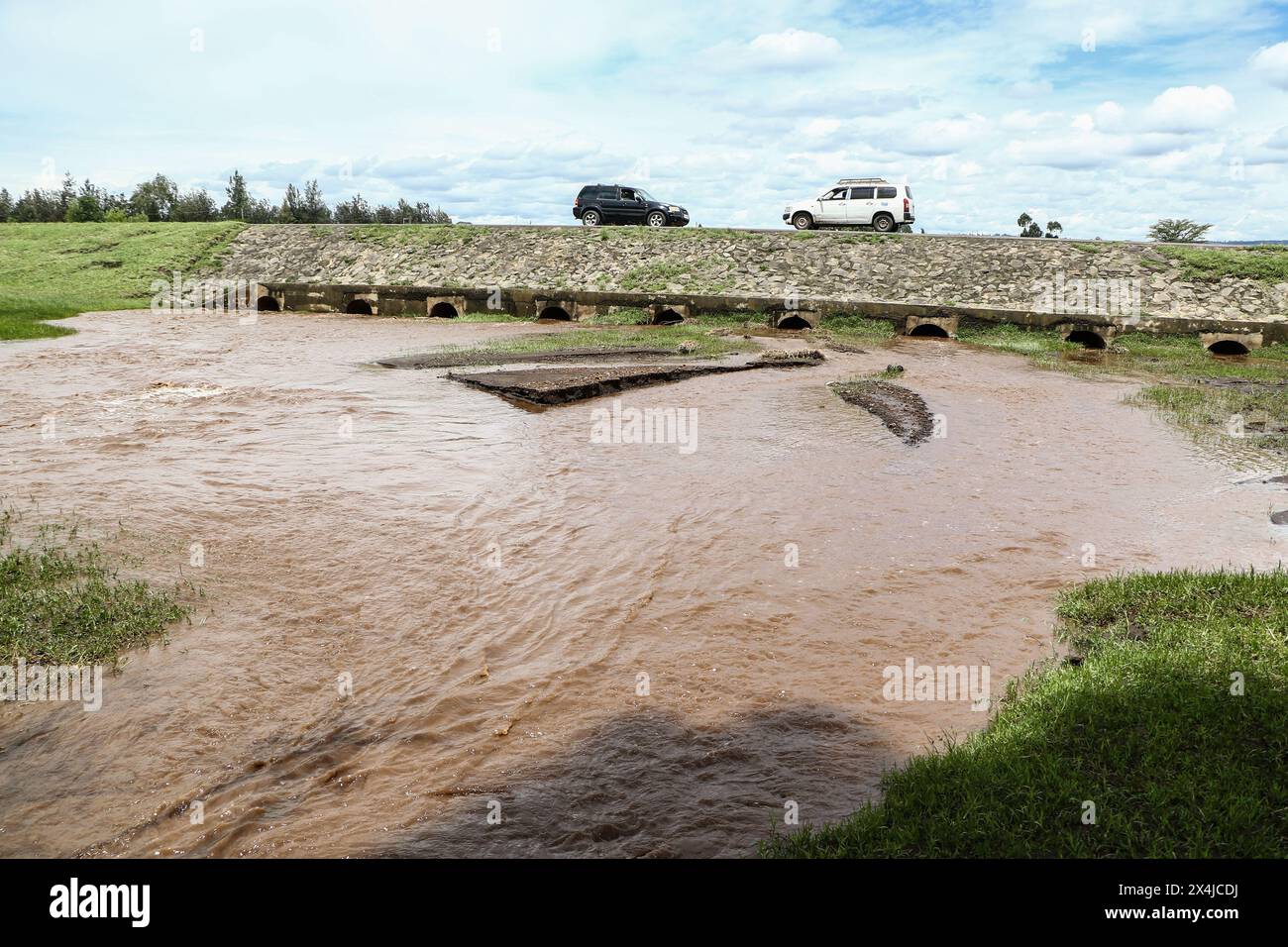 Vehicle drives past a flooded river Rongai, Nakuru County, following ...