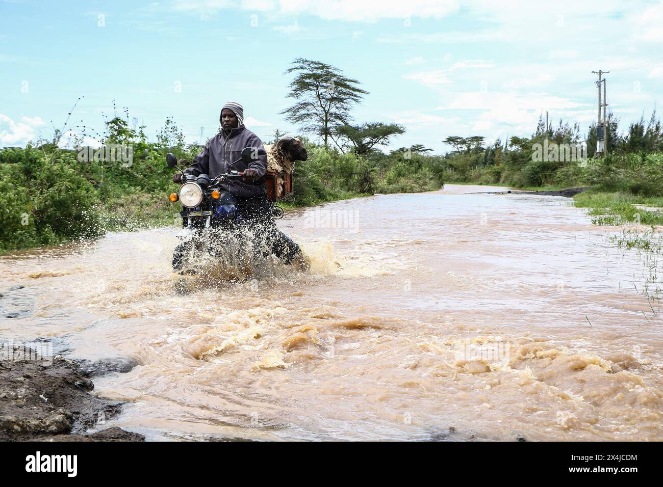 A man rides his motorcycle in a flooded road in Rongai, Nakuru County ...