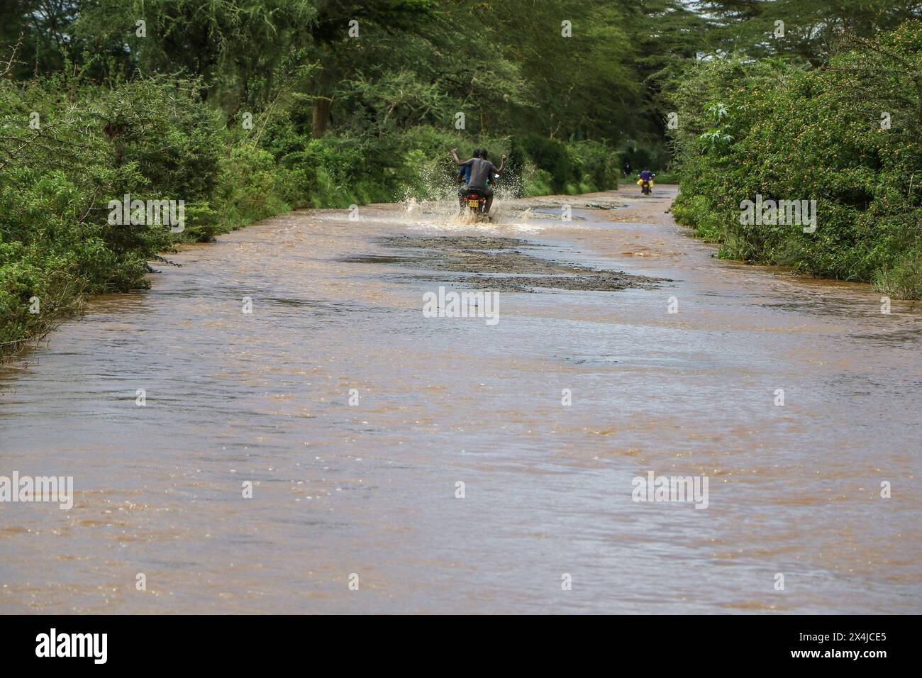 A man rides his motorcycle in a flooded road in Rongai, Nakuru County ...