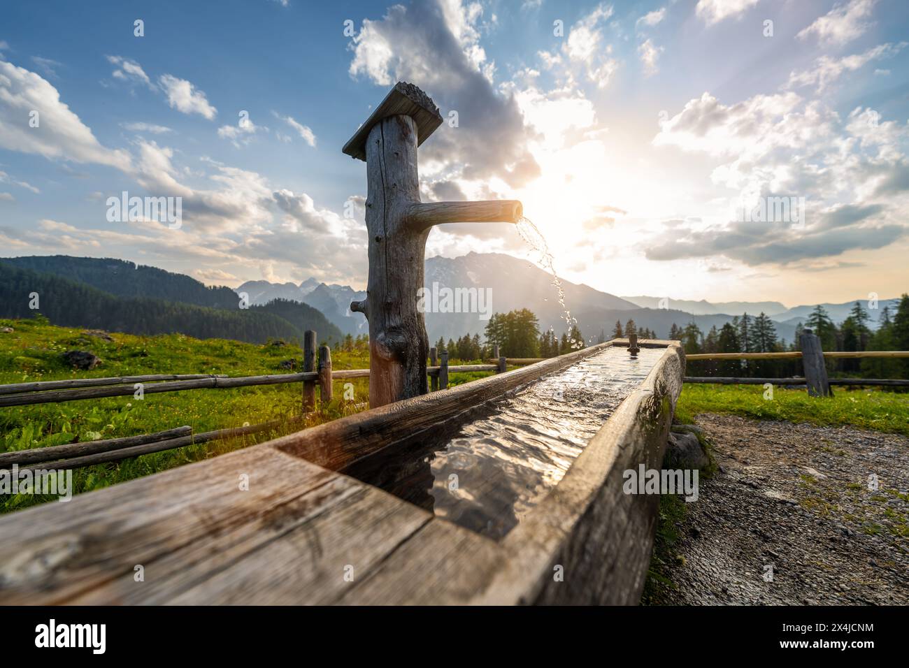 Wooden drinking trough with flowing water on a hut cabin. In the Alps ...