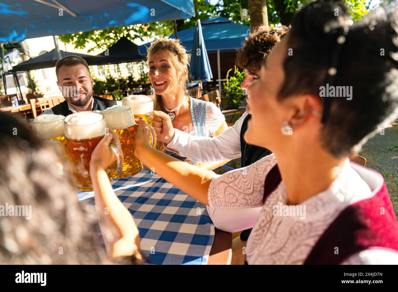 People toasting with beer at outdoor table in traditional outfits in a ...