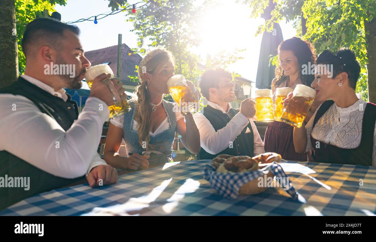 Group of people in traditional attire drinking beer at beer garden or ...