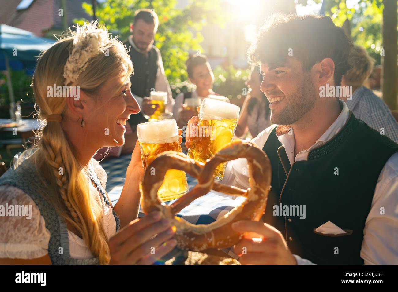 Couple in traditional German attire or tracht, holding beer mugs and ...