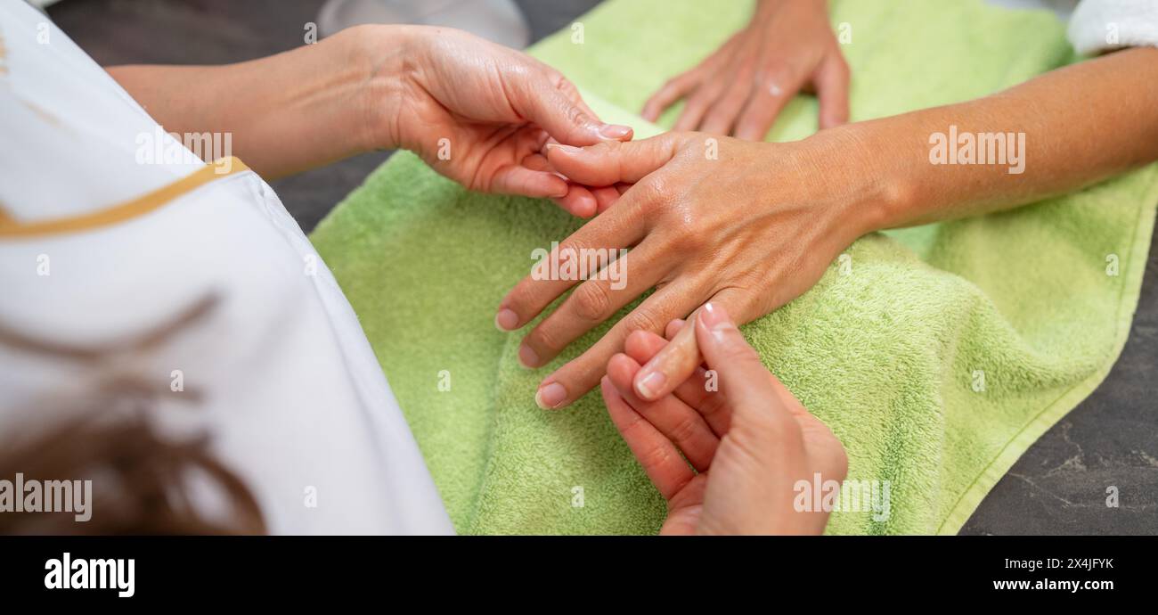 Manicurist massaging female client hand during a manicure session in a ...