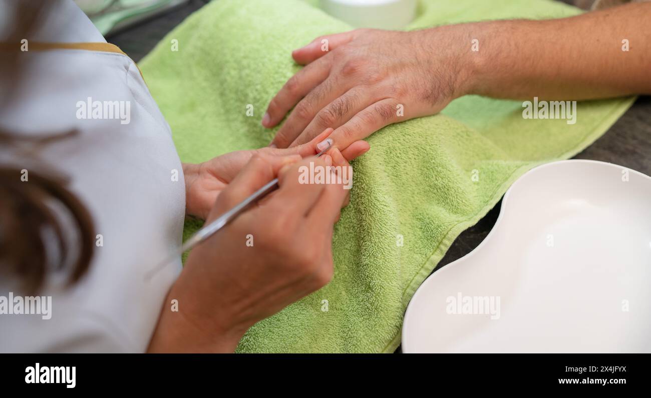 Close-up of a manicure with a manicurist cleaning cuticles on a client ...