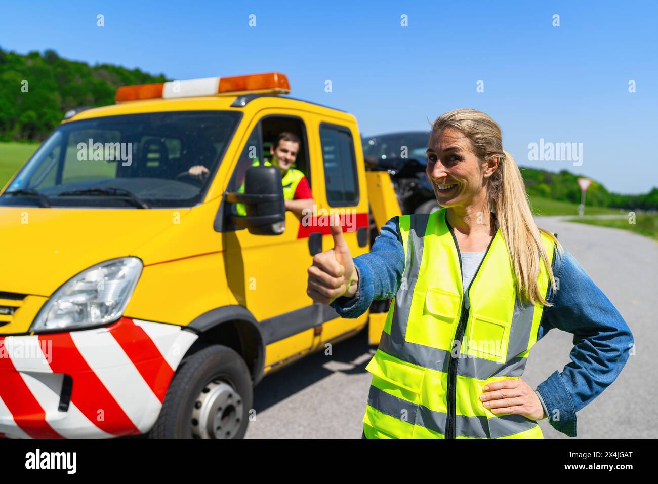 Woman showing thumbs up after a car breakdown with tow truck and driver ...