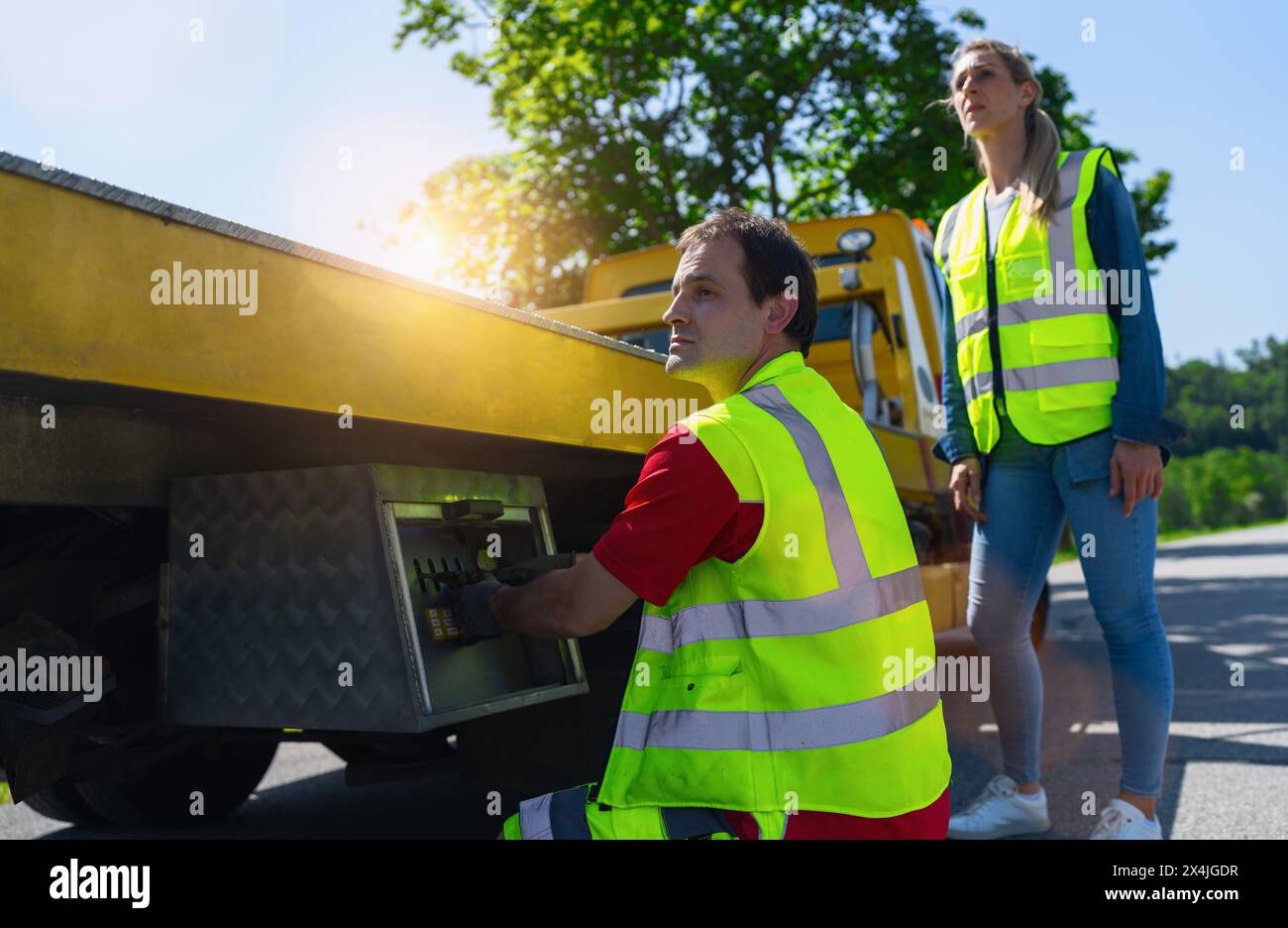 Tow truck driver operates the lifting ramp on a tow truck to tow the ...