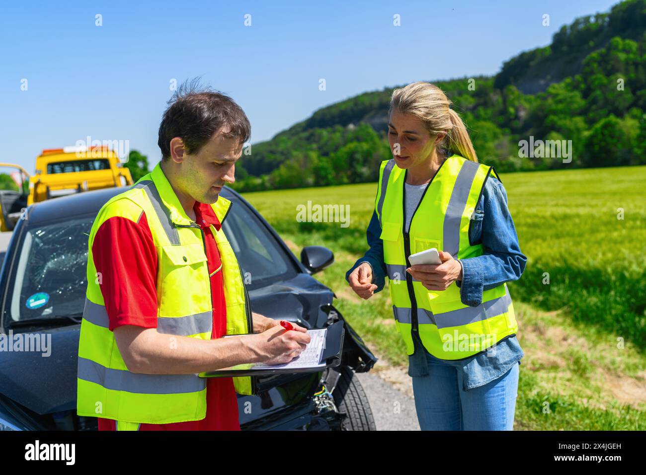 Roadside assistance worker filling out paperwork with customer against ...