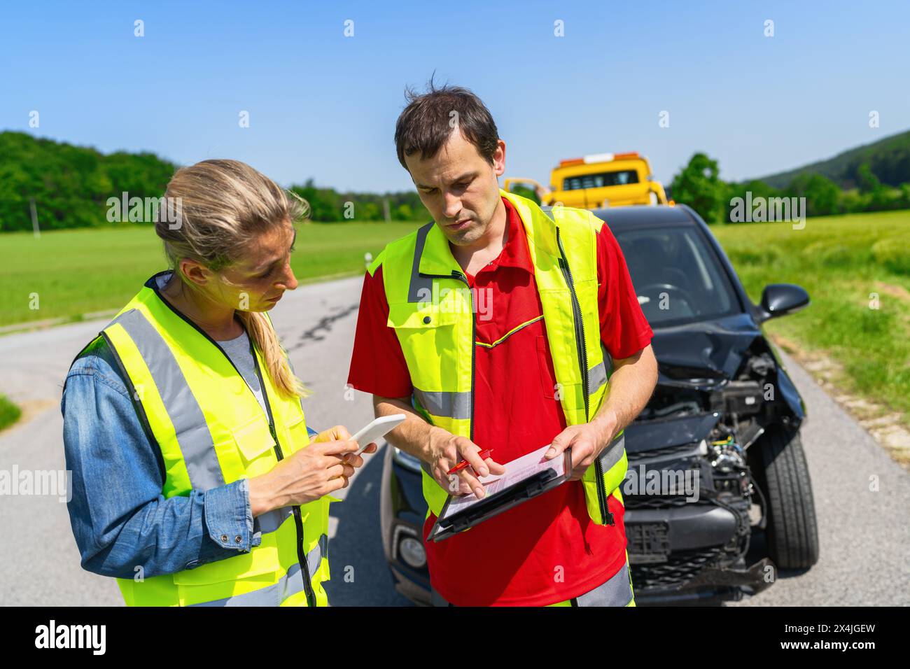 Roadside assistance worker filling out paperwork on a clipboard with ...
